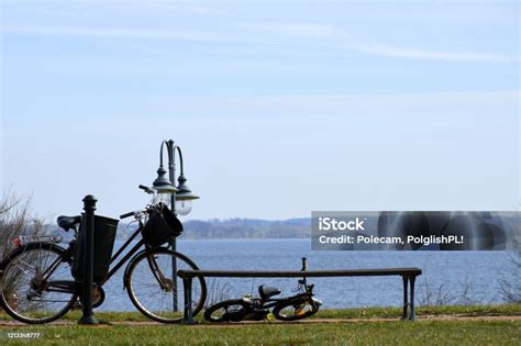 폴란드의 구름 없는 봄날 나무 벤치 가로등 기둥 쓰레기 옆에 서 있는 두 대의 자전거 어른 1명과 어린이 1대의 모습 건강한 생활방식에 대한 스톡 사진 및 기타 이미지