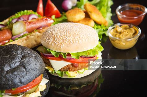 맛있는 패스트 푸드 소고기 버거 커틀릿 튀긴 양파 시금치 케첩 소스 블루 치즈를 전통적인 빵에 곁들인 햄버거 2개가 어두운 나무 배경 위에 나무 도마위에 올려져 있습니다