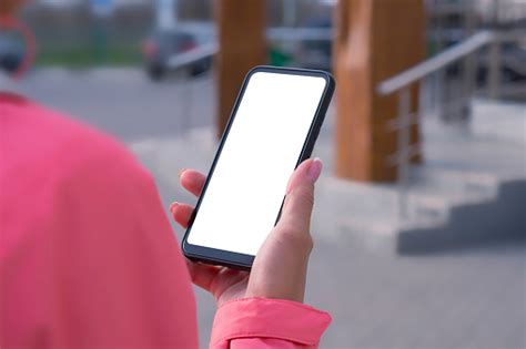 분홍색 재킷을 입은 소녀는 흰색 화면이 달린 스마트폰 모형을 손에 들고 있습니다 모형 기술 개념에 대한 스톡 사진 및 기타