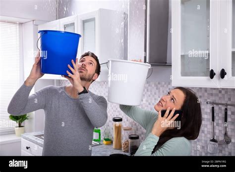 Worried Young Woman Calling Plumber On Cellphone While Man Collecting