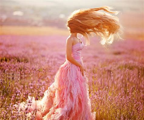 یک دختر سبزه زیبا با یک دسته گل بنفش که برهنه روی زمینه شعاعی از لوپین های صورتی سفید و بنفش