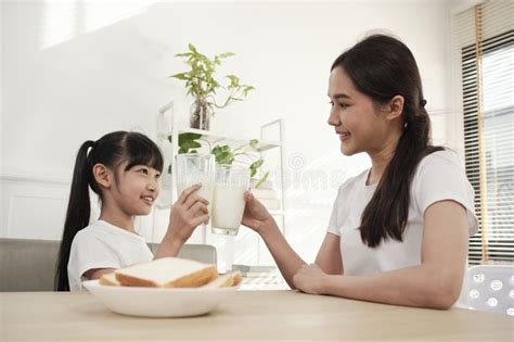 A Healthy Asian Mum And Daughter Drink Fresh Milk Together At A Dining