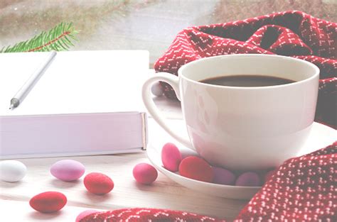 따뜻한 스카프와 흰색 책 옆에 있는 나무 창틀에 여러 가지 색상의 과자를 곁들인 화이트 커피 한 잔 가정의 방에 대한 스톡 사진