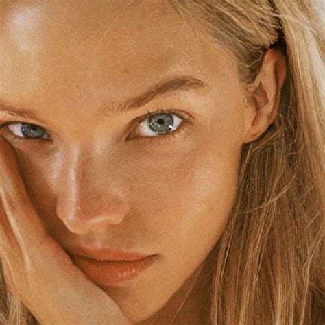 A Close Up Of A Woman With Blue Eyes And Blonde Hair Looking At The Camera