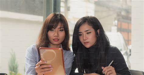 일대일 회의 카페의 테이블에 앉아 있는 두 명의 젊은 비즈니스 여성 소녀는 노트북 화면에 동료 정보를 보여줍니다 스마트폰 블로깅을 사용하는 소녀 팀워크 비즈니스 회의