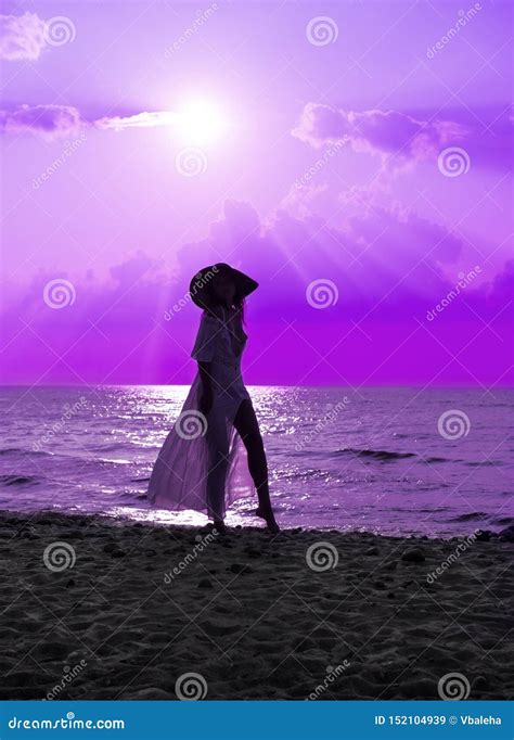 Silueta De La Mujer Desnuda Joven Hermosa En El Vestido Blanco Que Presenta En La Playa En La