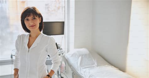 그녀의 사무실에 서 있는 그녀의 유니폼 주머니에 그녀의 손을 가진 사랑스러운 검은 머리 여성 의사 사진 Unsplash의 병원 침대 이미지