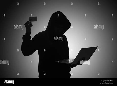 Mysterious Man Wearing Black Hoodie Using Laptop And Holding Credit Card In The Dark Room