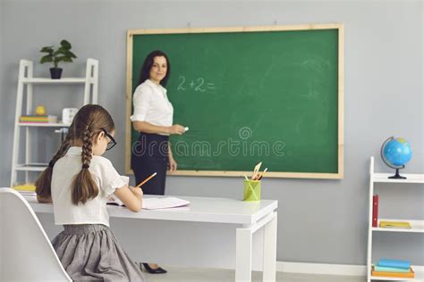 Enseignant De Lécole Primaire Au Tableau Noir Et écolière écrivant