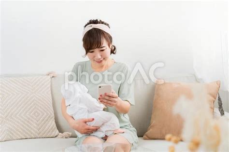 赤ちゃんを抱っこしながらスマホを使う女性 No 25251774｜写真素材なら「写真ac」無料（フリー）ダウンロードok