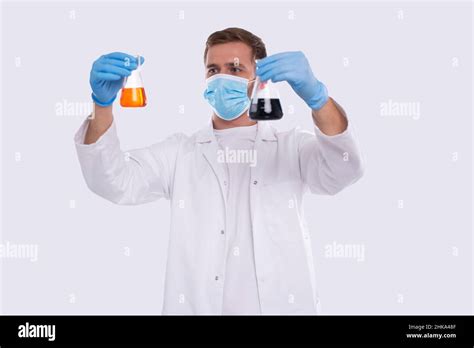 Male Doctor Examing Flask With Colorfull Liquid Wearing Medical Mask