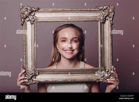 Millenial Young Woman Blonde Hair Holds Gilded Picture Frame In Hands
