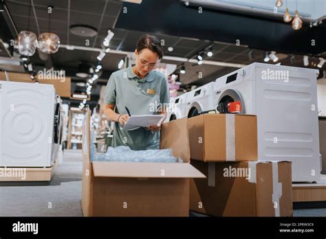 Female Writing In Document Over Open Cardboard Box While Working In