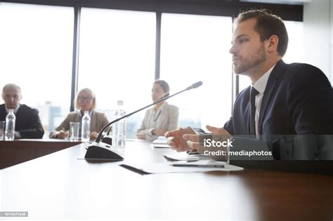 벌 나무 테이블에 앉아 및 개발의 계획 회의에서 기자 들과 공유 하는 동안 마이크에 말하기에 심각한 자신감 잘생긴 젊은 사업가