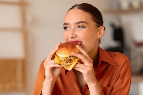Premium Photo Joyful Woman Enjoying A Bite Of Her Tasty Burger