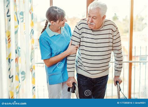 Enfermera Ayudando A Un Anciano Con Un Marco Para Caminar En Un Asilo