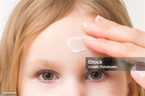 젊은 성인 어머니 손가락이 유아 소녀 이마에 흰색 보습 크림을 바르고 있습니다 아기 얼굴 피부에 대한 일상적인 관리 근접 촬영 정면도 2명에 대한 스톡 사진 및 기타 이미지