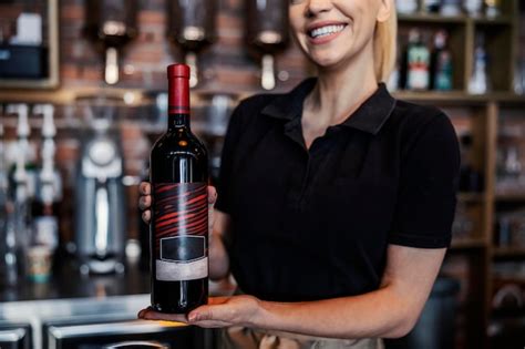 Centrarse en una botella de vino sosteniendo manos femeninas promoción
