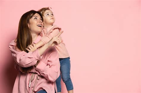 꿈을 분홍색 스튜디오 배경에 고립 된 젊은 여성과 어린 소녀 어머니와 딸의 초상화 어머니의 날 축하 가족 어린 시절 모성의 개념