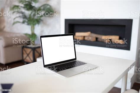 벽난로와 녹지의 배경에 대한 내부의 흰색 테이블에 빈 화면이있는 노트북 텍스트 장소와 배경 콘텐츠인 콘텐츠를 추가하기 위한