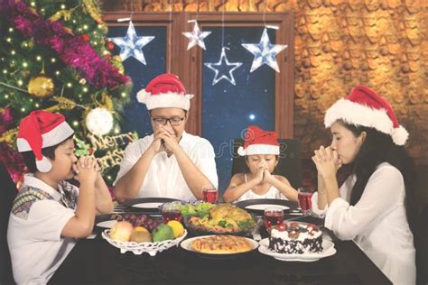 Familia Joven Que Ruega En La Navidad De La Cena Imagen De Archivo