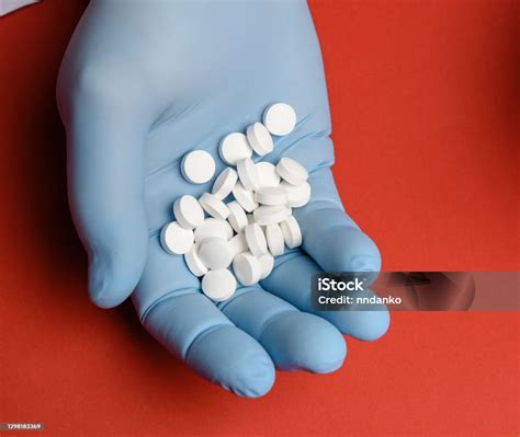 파란색 멸균 고무 장갑에 남성 손은 빨간색 배경에 알약의 스택을 보유 알약에 대한 스톡 사진 및 기타 이미지 알약 장갑 개념 Istock