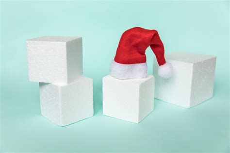 최소한의 구성 겨울 개체 산타 모자와 큐브 모양 기하학적 양식 연단 고립 된 블루 파스텔 배경 크리스마스 새해 12 월 시간 축