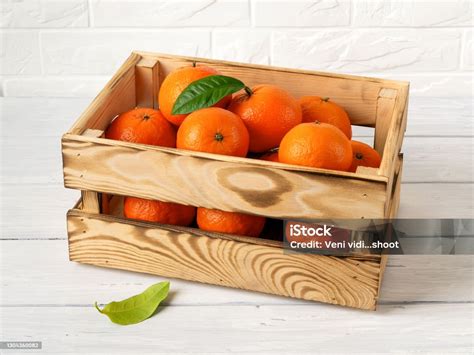 부엌 테이블에 달콤한 잘 익은 오렌지 귤 나무 상자 나무 상자에 신선한 감귤류 과일과 채소를 위한 친환경 소박한 스타일의 용기 채식과 건강한 식사 감귤에 대한 스톡 사진 및