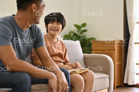 귀여운 아시아 소년은 거실에서 아빠와 함께 소파에 앉아 함께 가족 시간을 보낸다 2명에 대한 스톡 사진 및 기타 이미지 2명