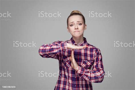 분홍색 체크 무늬 셔츠에 아름 다운 금발 여자 수집 롤빵 헤어스타일 서 타임 아웃 제스처와 함께 카메라를 바라보 고 더 많은