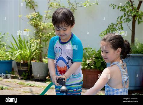 Siblings Playing With Water In The Backyard On A Hot Summer Day Stock