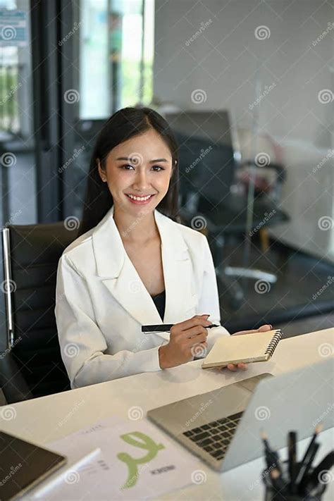 A Female Assistant Or Secretary Sits At Her Desk With Her Notebook And