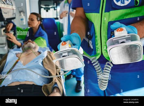 Paramedic Preparing Defibrillator For Cardiopulmonary Resuscitation Of