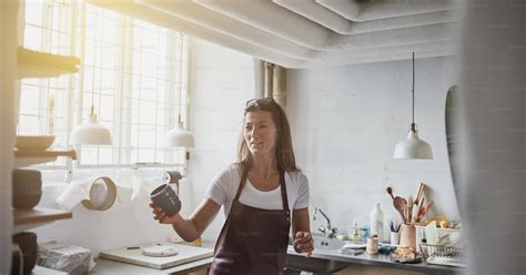 새로 만든 유약 도자기 조각을 들고 창의적인 작업장에 홀로 서 있는 웃는 여성 장인 사진 Unsplash의 부엌 이미지