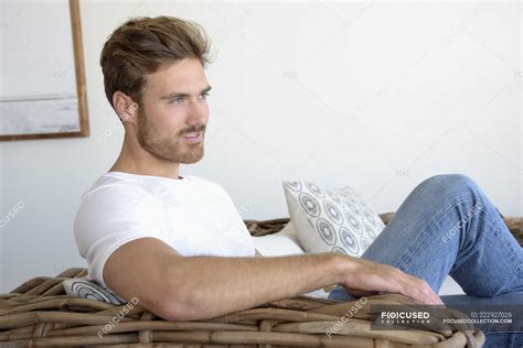 Happy Young Man Relaxing On Sofa At Home — Sitting Looking Away
