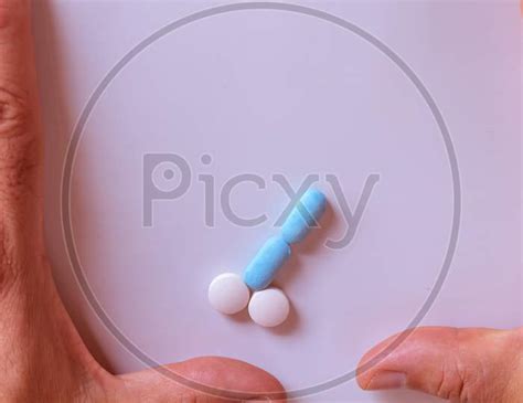 Image Of Hands Of A Man Next To Pills That Symbolize A Penis With An