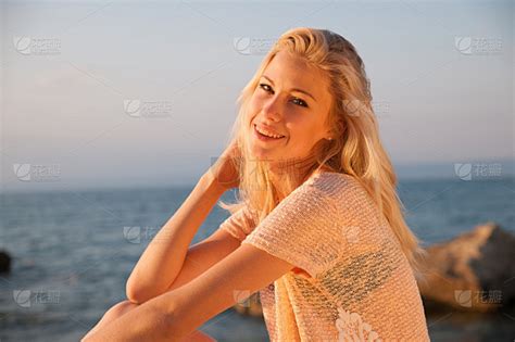 日落时分，美丽的金发女郎在海滩上休息