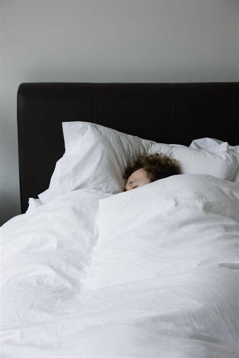 Man Sleeping In Bed Covered Under Duvet Elevated View Stock Image