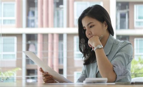Portrait Of Businesswoman Sitting At Office Desk And Checking Documents