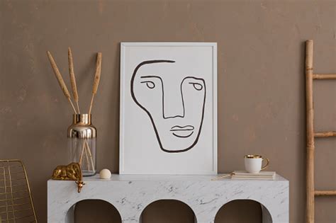 모형 포스터 프레임 대리석 콘솔 사다리 말린 꽃이 달린 황금 꽃병 갈색 벽 조각품 및 개인 액세서리가 있는 거실 인테리어의