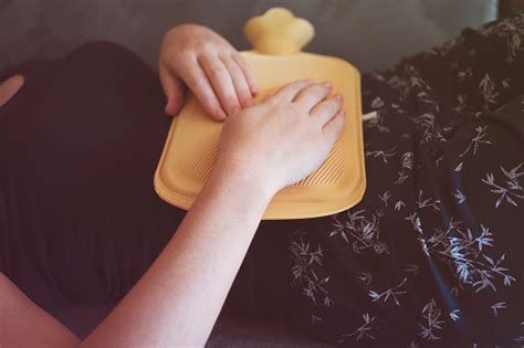 젊은 여자 거짓말 에 소파 들고 노란색 뜨거운 물 가방 에 위 에 홈 20 24세에 대한 스톡 사진 및 기타 이미지 20