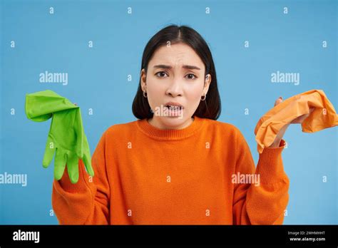 Confused Asian Woman Showing Two Latex Gloves Complains At Cleaning