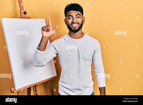 Arab Man With Beard Standing By Painter Easel Stand Smiling With An