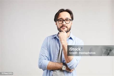 캐주얼 셔츠와 안경을 입고 생각에 턱을 만지는 수염을 가진 젊은 아시아 남자의 콘텐츠 진취적인 초상화 스튜디오 촬영에 대한 스톡