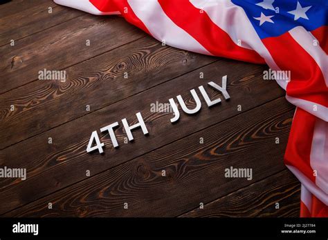The Words 4th July And Crumpled Usa Flag On Flat Textured Wooden