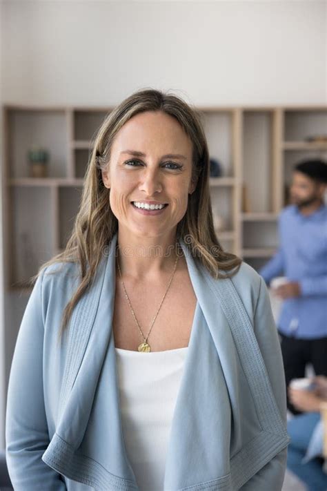 Happy Middle Aged Business Leader Woman Standing In Office Space Stock