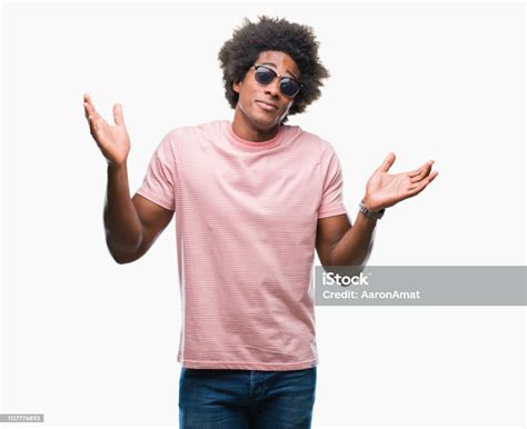 아프리카 미국 남자는 팔과 손을 제기와 고립 된 배경 덩어리와 혼동 표현 위에 선글라스를 착용 의심의 개념입니다 감정에 대한
