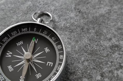 Premium Photo Magnetic Compass Laying On Stone Surface And Pointing