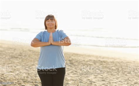 아침 일출에 바다 해변에서 호흡 운동을 연습하는 성숙한 여성의 요가와 명상 몸의 마음과 정신 마음챙김 개념 깨달음과 건강한 생활 방식 50 54세에 대한 스톡 사진 및 기타