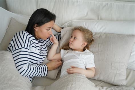Mãe Deitada Na Cama Confortável Com Pequena Filha Adotiva No Quarto